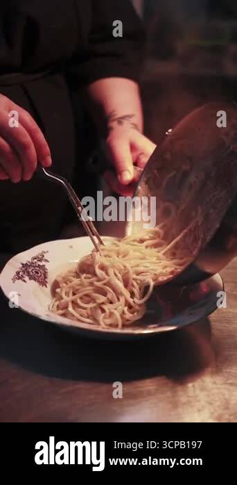 Vertical video. Serving pasta. Traditional italian dish. Chef putting ...