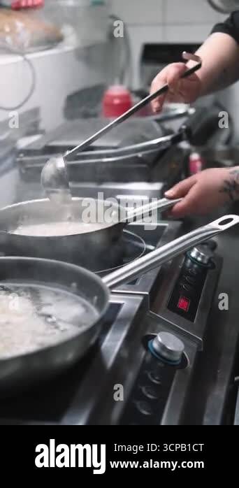 Vertical video. Stewing dish. Hot sauce. Chef hand adding ladle water ...