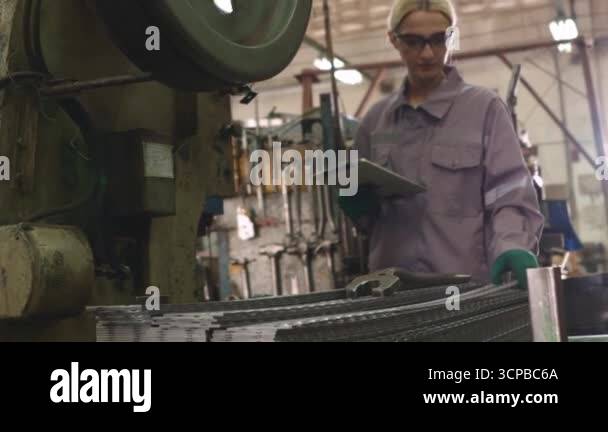 Female lathe operator wearing safety glasses chips and holding ...