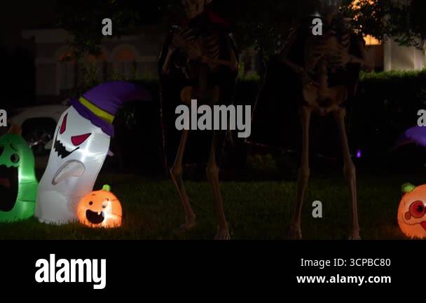 Two skeleton musicians in top hats and capes stand in a Halloween yard ...