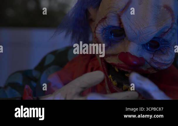 Close-up portrait of a scary Halloween clown with glowing spiral eyes ...