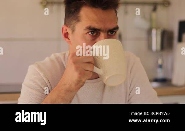 A man sits at home, leisurely sipping coffee from a large mug while ...