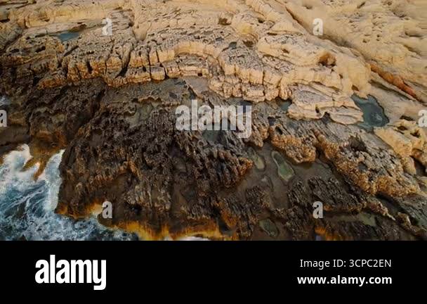 Woman explores tidal rock pools along rugged coast by sea in Greece at ...