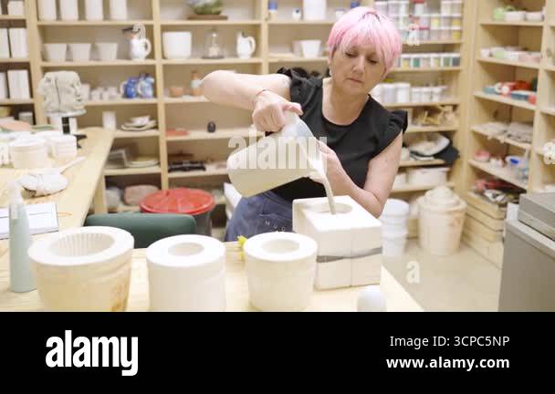 Skilled ceramic artist carefully pouring liquid slip into plaster mold ...