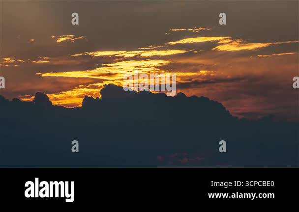 Time lapse of a sunrise over dramatic stormy clouds, with golden light ...