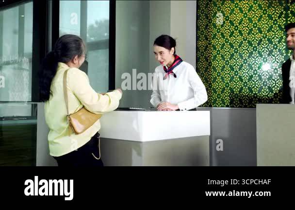 Smiling airline staff assists senior female passenger at airport check ...