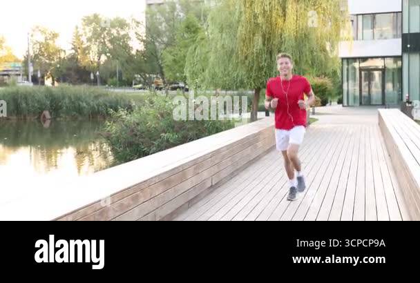 Athletic man running near lake in park Stock Video Footage - Alamy