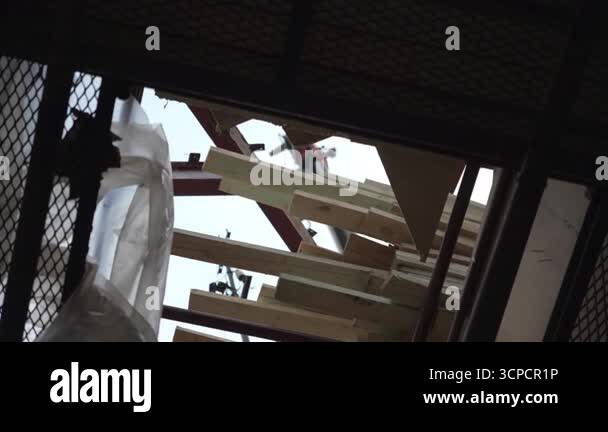 Damaged roof opening reveals massive crane slowly lifting steel boom ...