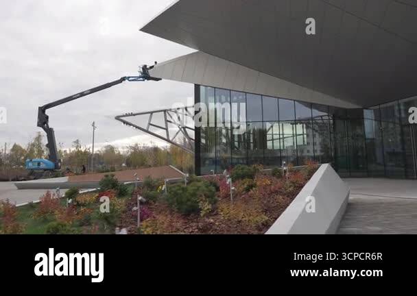 Elevated workers perform cladding work with steady rhythm. Team applies ...