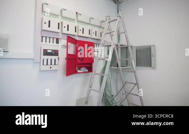Ladder stands near red electric panel in house corridor. Scene ...