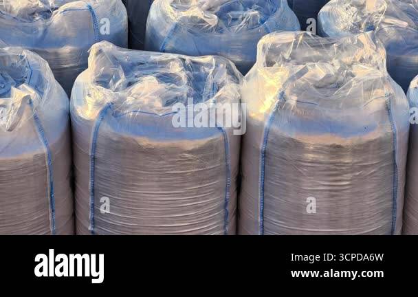 Stacked bags containing various goods are wrapped in protective plastic ...