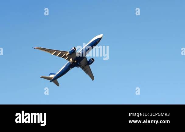 Commercial airplane in low flight against a clear blue sky, viewed from ...