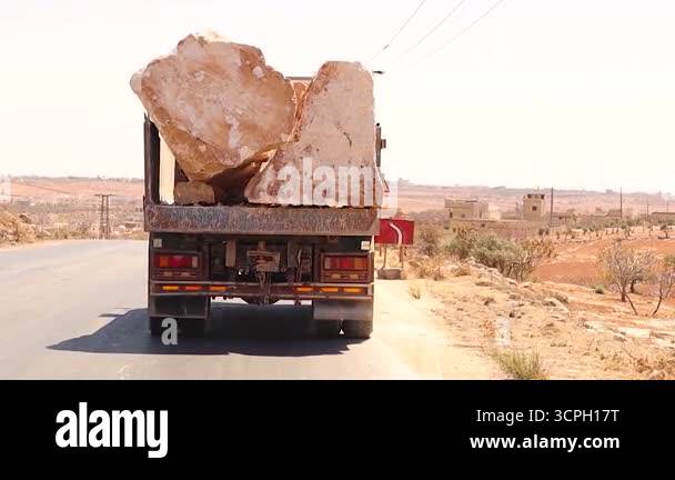 Truck loaded with huge stones driving on a rural road without safety ...