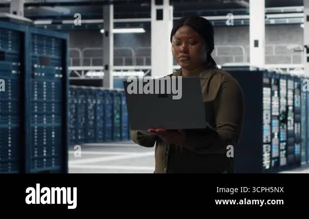 Data center engineer using laptop to develop disaster recovery plans, minimizing downtime ...