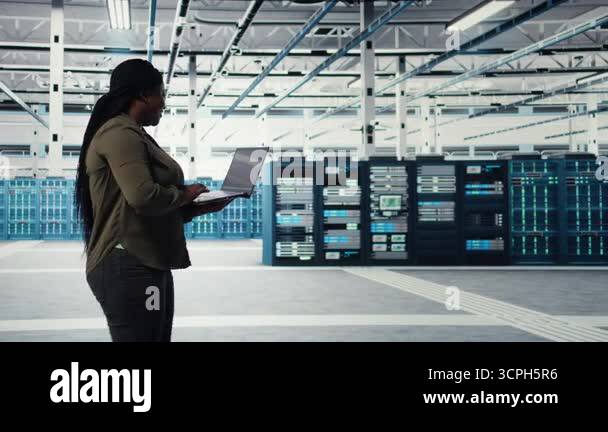 Data center worker using laptop to manage software updates for system ...