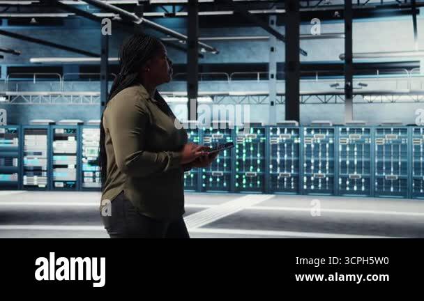 Data center technician monitors data center metrics on tablet to ...