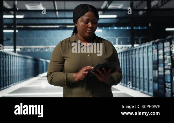 Data center engineer monitors data center metrics on tablet to enhance ...