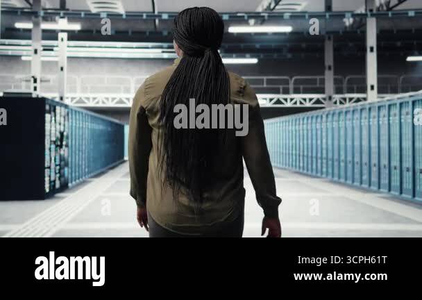 Woman walking through data center server rows, checking equipment for ...
