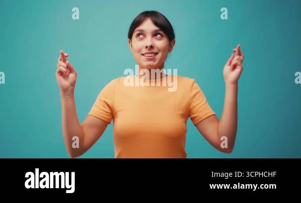 Emotional Hispanic young woman makes wish looking upward on blue ...