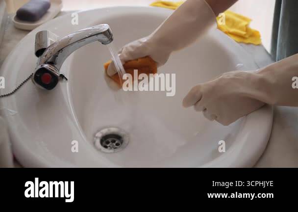 Close-up of an adult woman rinsing and wringing a yellow microfiber ...