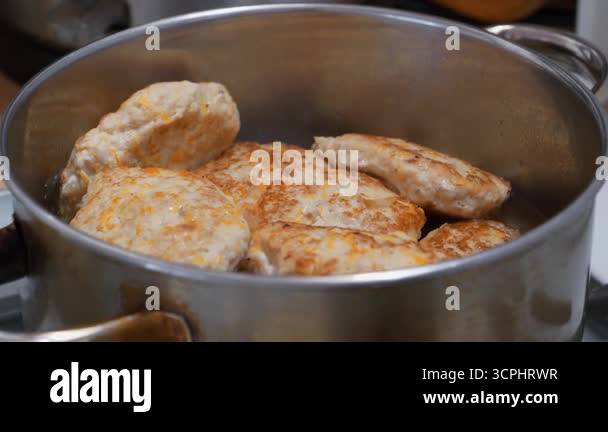 Meat cutlets are stewed in saucepan after being fried in frying pan ...