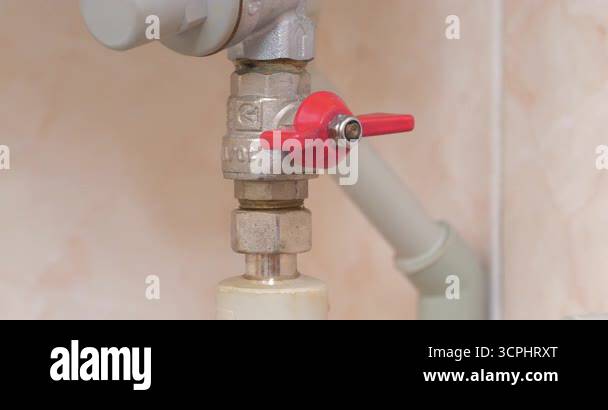 Red valve on the cold water pipe to the boiler for heating. Man turns ...