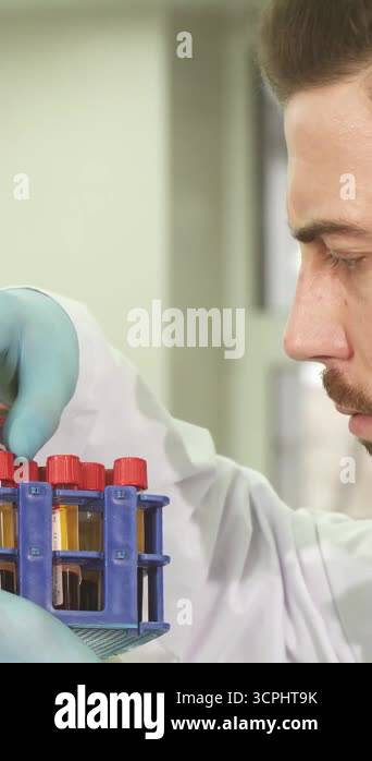 A dedicated young man in a crisp white lab coat and blue latex gloves ...