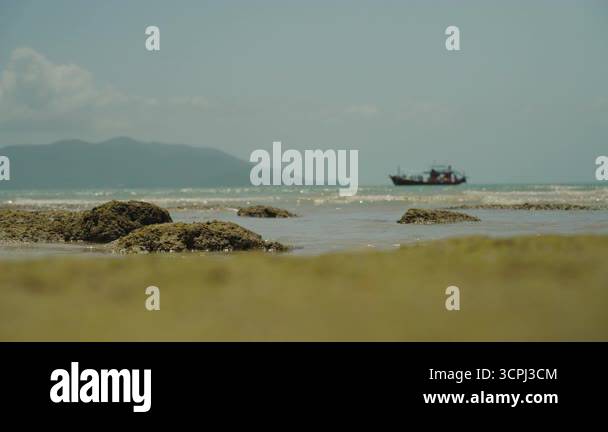 Fishing Boat Floating on Shallow Sea Near Rocky Shore With Distant ...