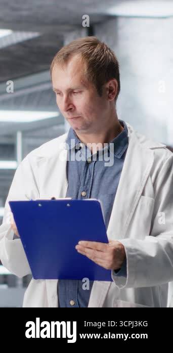 Vertical Video Portrait of confident male scientist checking clipboard ...