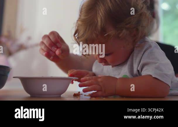 Close-up of toddler reaching across dining table during mealtime ...