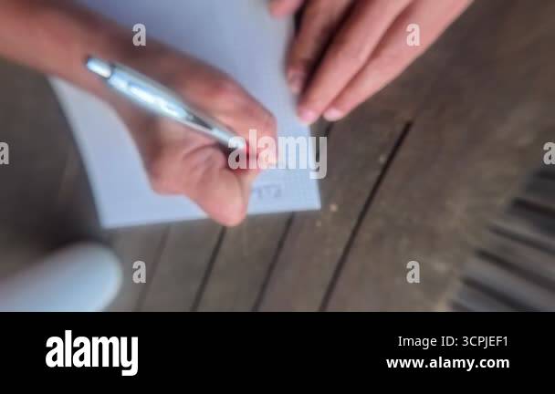 Hand writes a letter on a checkered block paper with a ballpoint pen ...