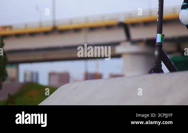Close up of a persons legs in knee pads riding a push scooter down a ...
