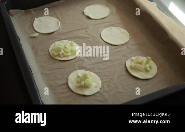 hands preparing mini pies with brie cheese, fresh apple slices, and ...