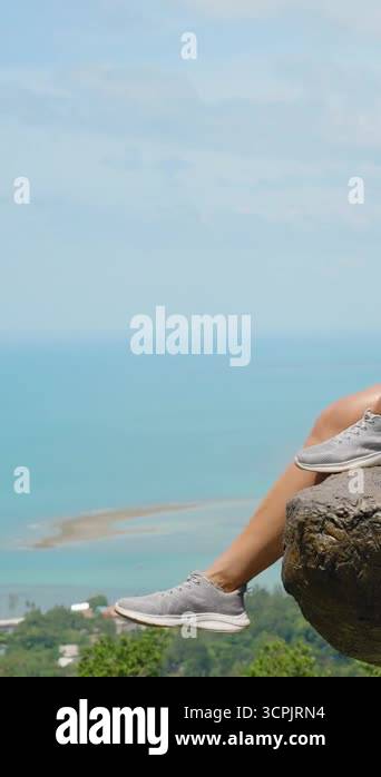 Vertical video. Young Woman Relaxing on Cliff Edge Leaning Back Under ...