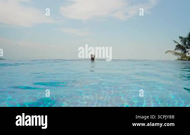 Woman Relaxing at Edge of Infinity Pool Looking at Horizon with Blue ...