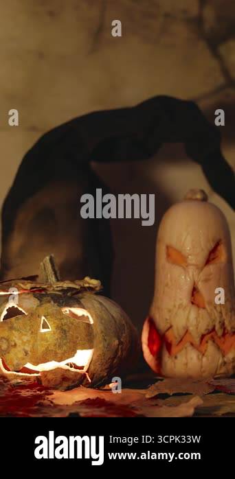 Vertical close-up video of two carved pumpkins. The camera slowly zooms ...
