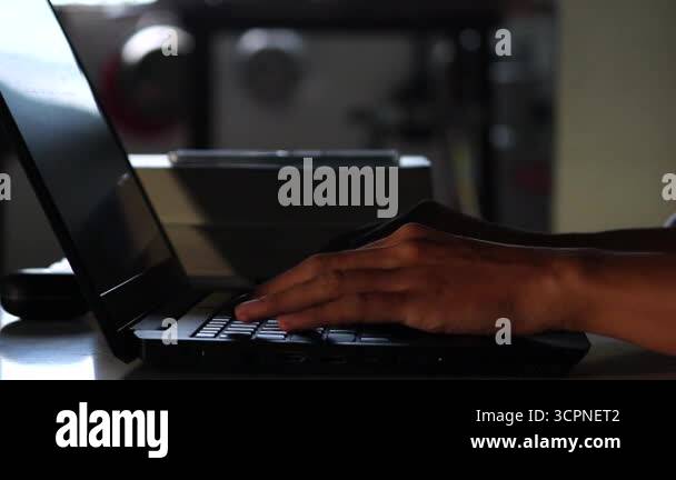 A real-time close-up video of a person's hands typing on a laptop ...