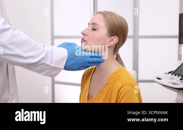 Thyroid gland exam and treatment. Doctor palpates of woman's neck for ...