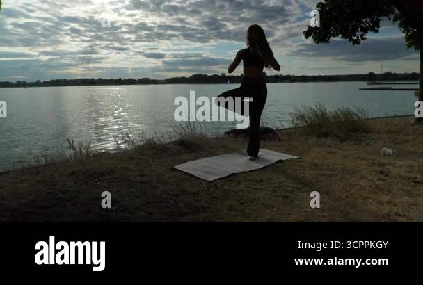 A beautiful silhouette performing various yoga poses on the sandy shore ...