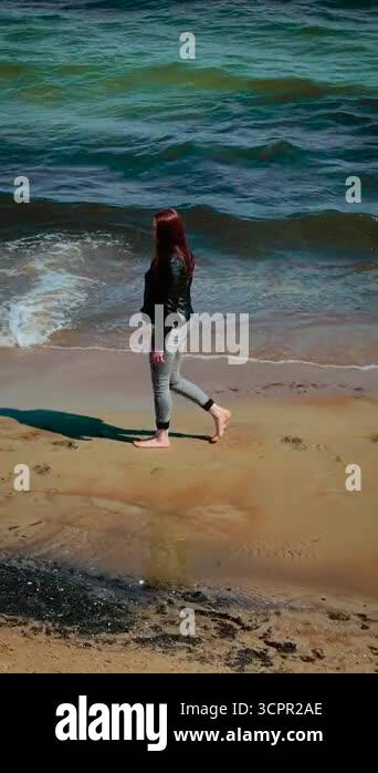 Woman walking on sandy beach near sea waves, vertical orientation ...