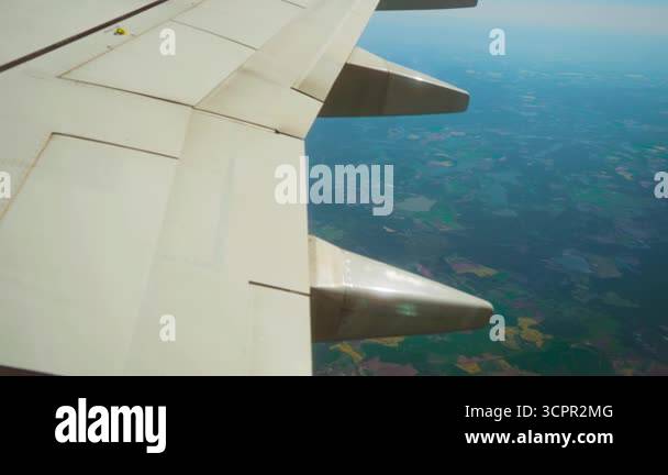 Airliner flying above green landscape with wing and flap track fairings ...