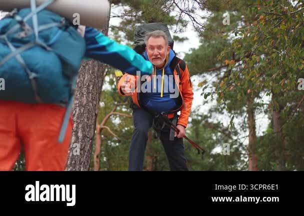 Hiking adventure. Man helping hand woman on hiking in forest. Senior ...