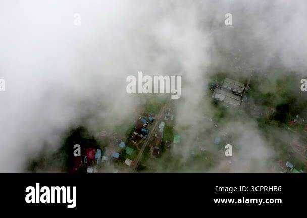 A cloudy sky with a town below. The town is made up of small houses ...