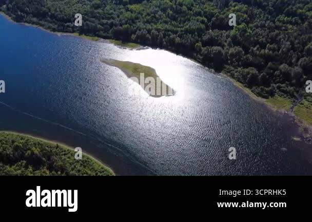 A sandbar forms an island with modest vegetation bathing in the center ...