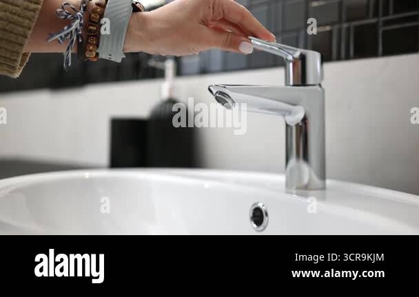 Girl Opens The Bathroom Sink Mixer Tap And Water Flows From The Faucet ...