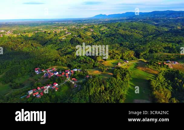 A small cozy village with cute houses and paved roads in a valley with ...