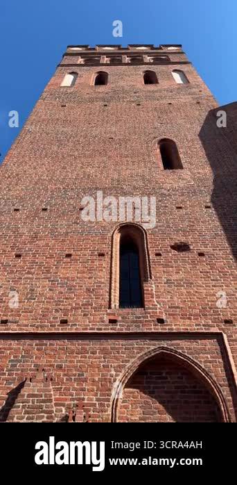 Vertical video of a tall medieval gothic brick church tower with narrow ...