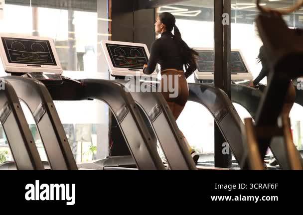 Fit girl exercises on a treadmill in a stylish gym setting, focusing on ...