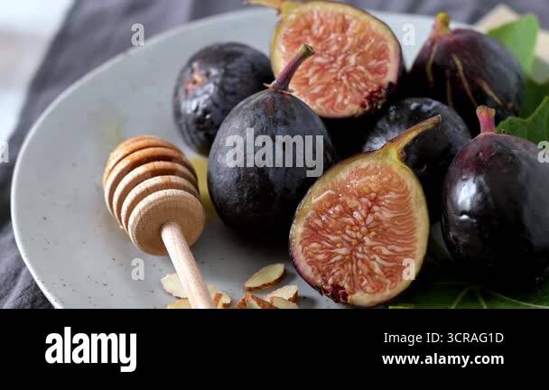 A rustic still life of fresh Black Mission figs, some whole and some ...