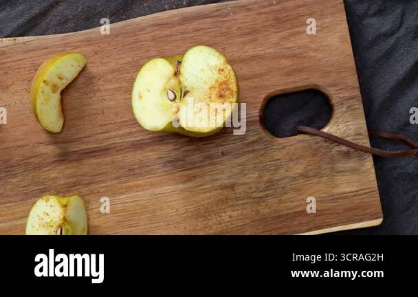 A half-cut apple and a smaller wedge, both dusted with cinnamon, rest ...